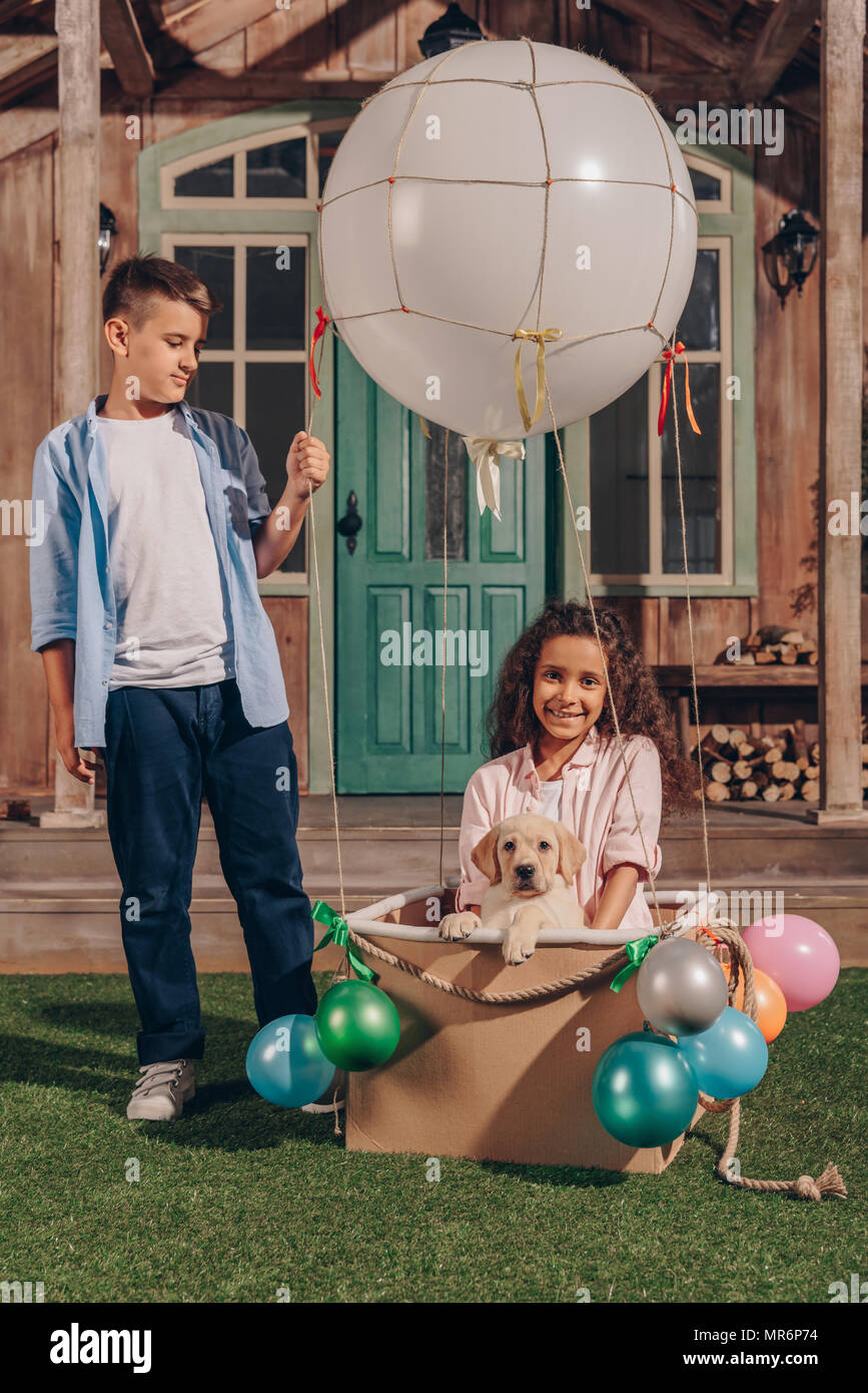 african american girl with labrador puppy sitting in air balloon box ...