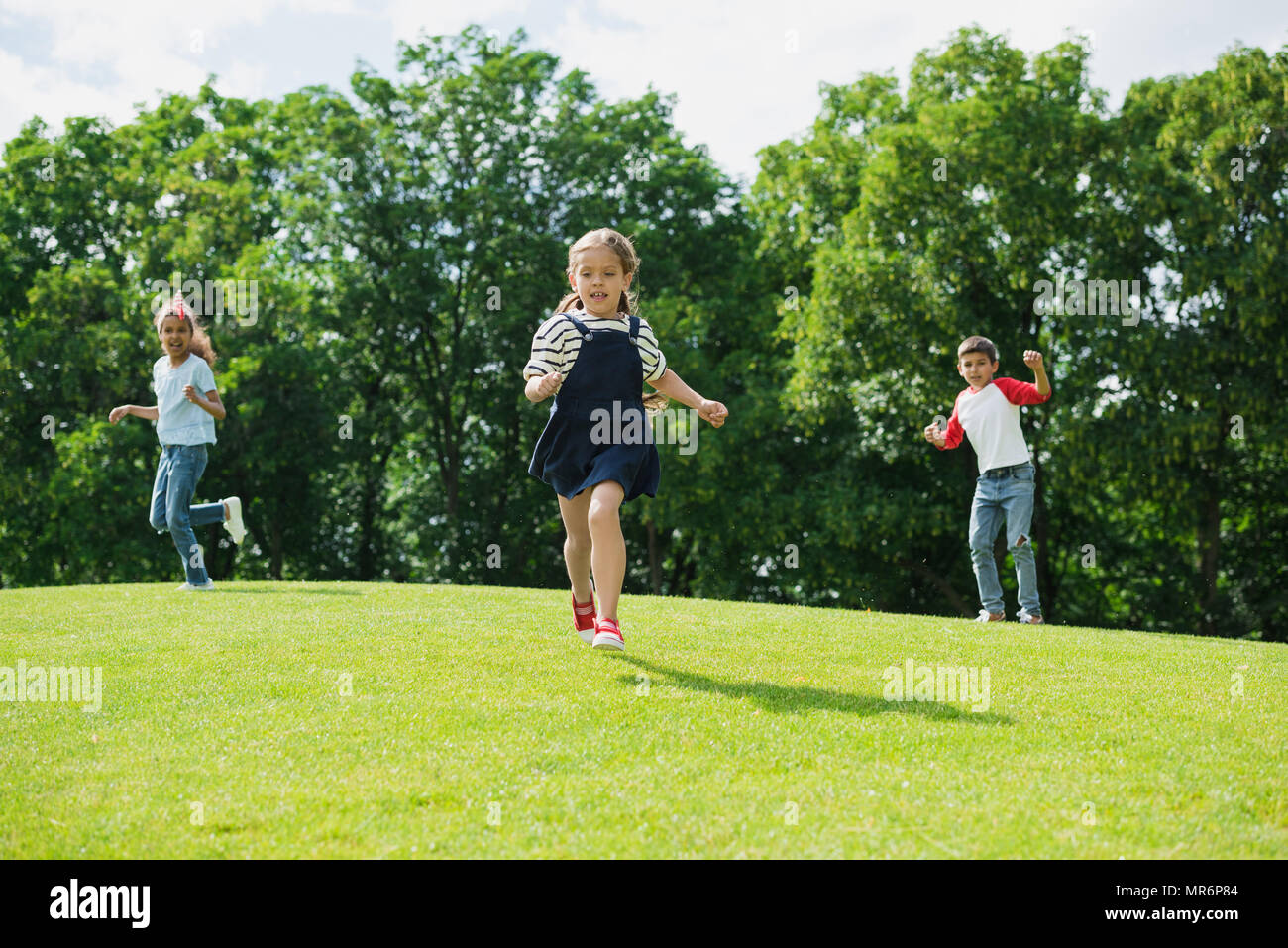 Adorable happy multiethnic kids playing and running together on green ...