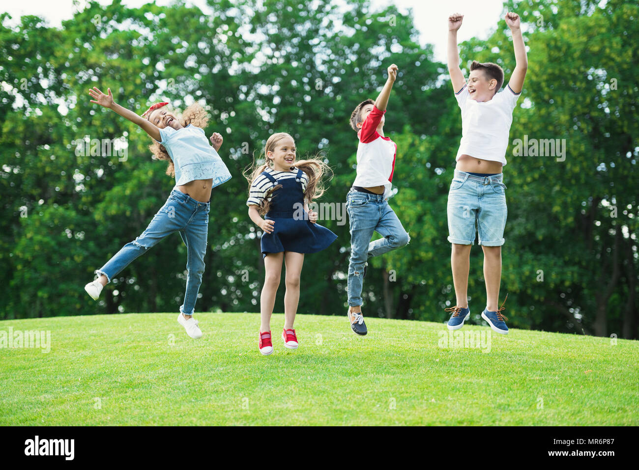 Happy kids jumping together in park hi-res stock photography and images ...
