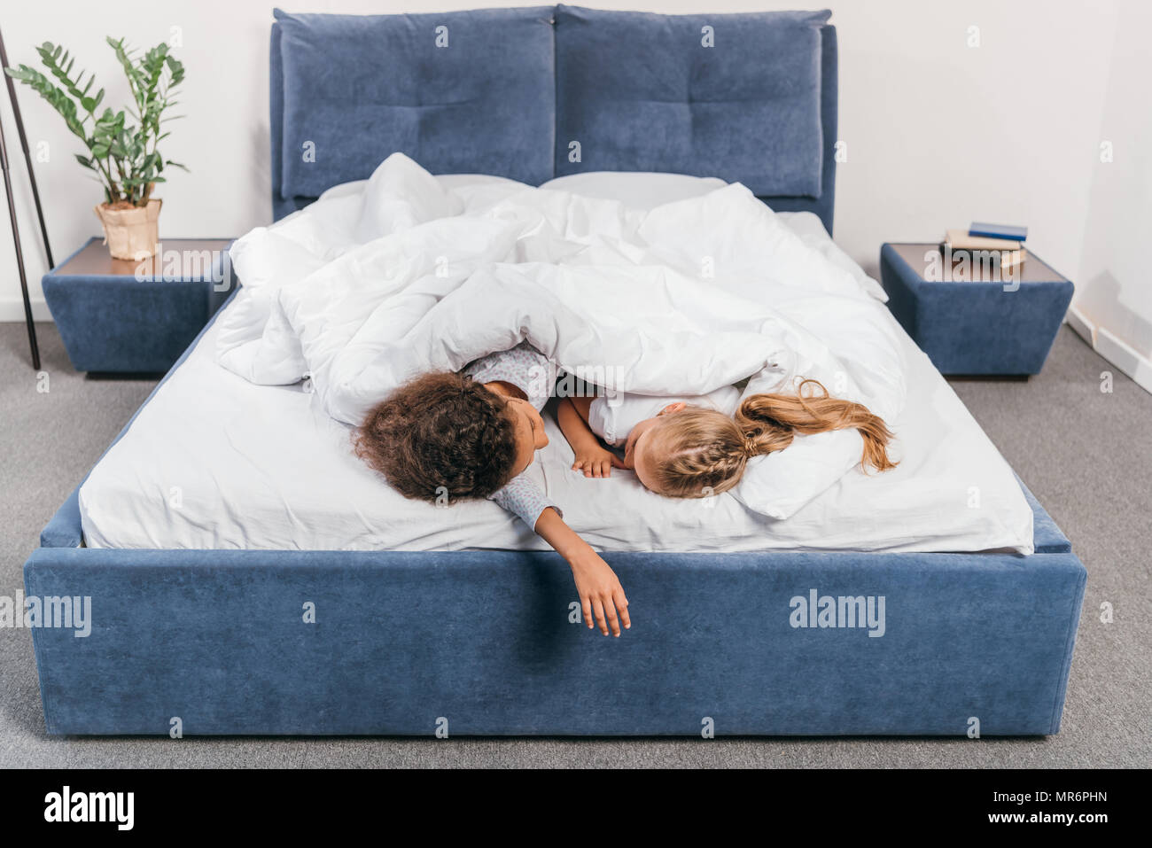 multicultural little girls sleeping in bed at home together Stock Photo ...