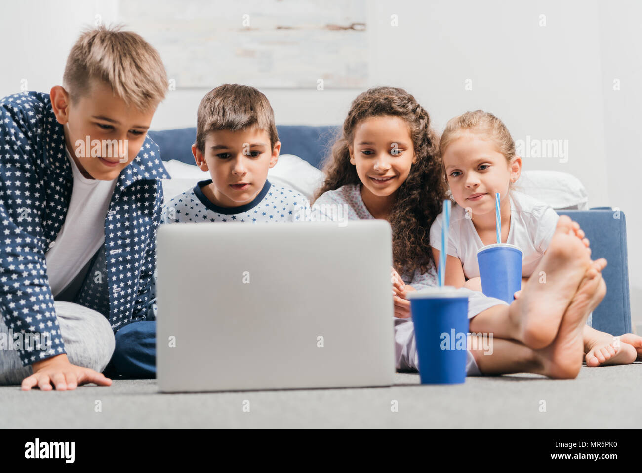 multicultural children resting and watching movie at home together ...