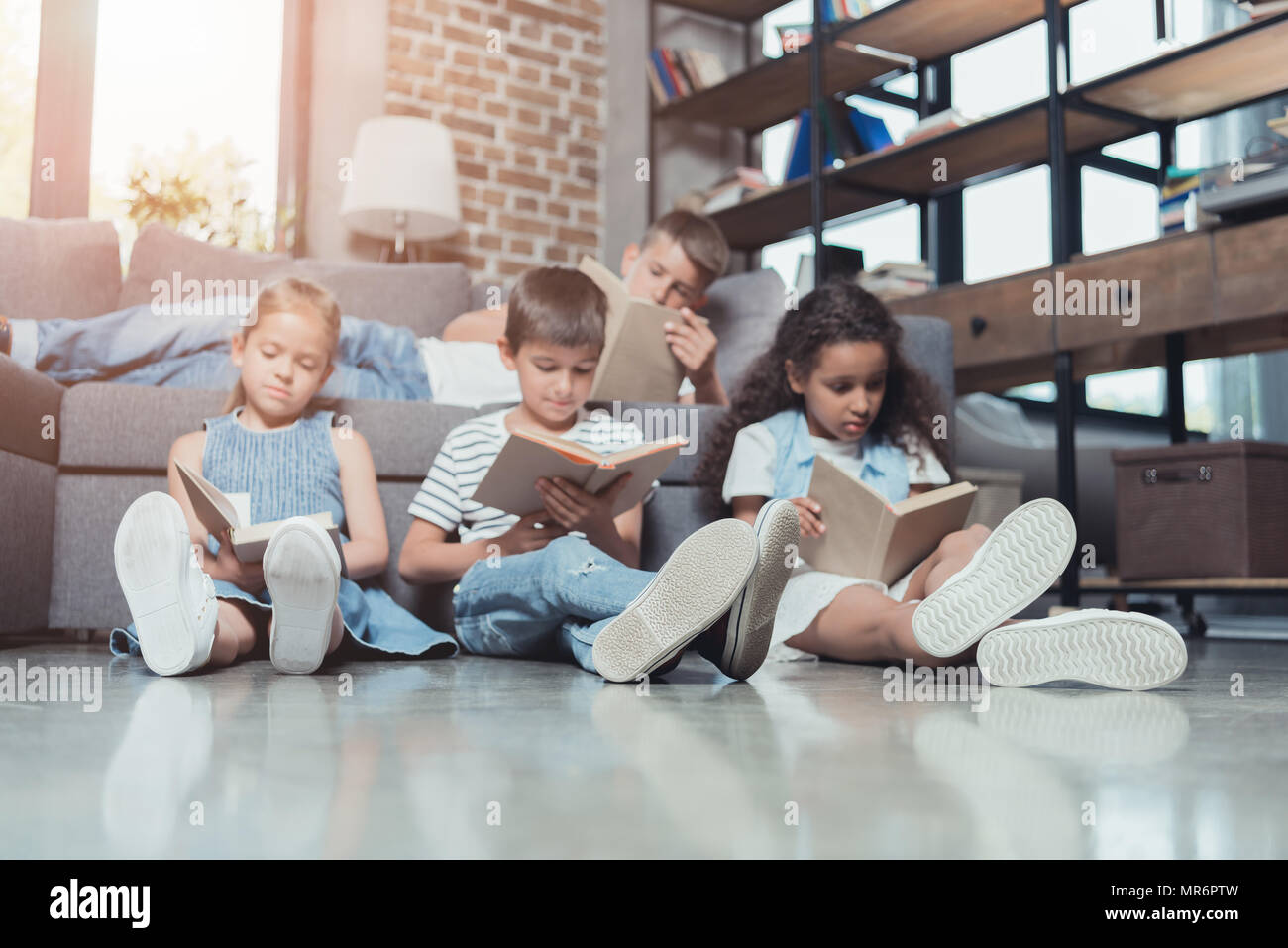 multicultural group of concentrated children reading books at home ...