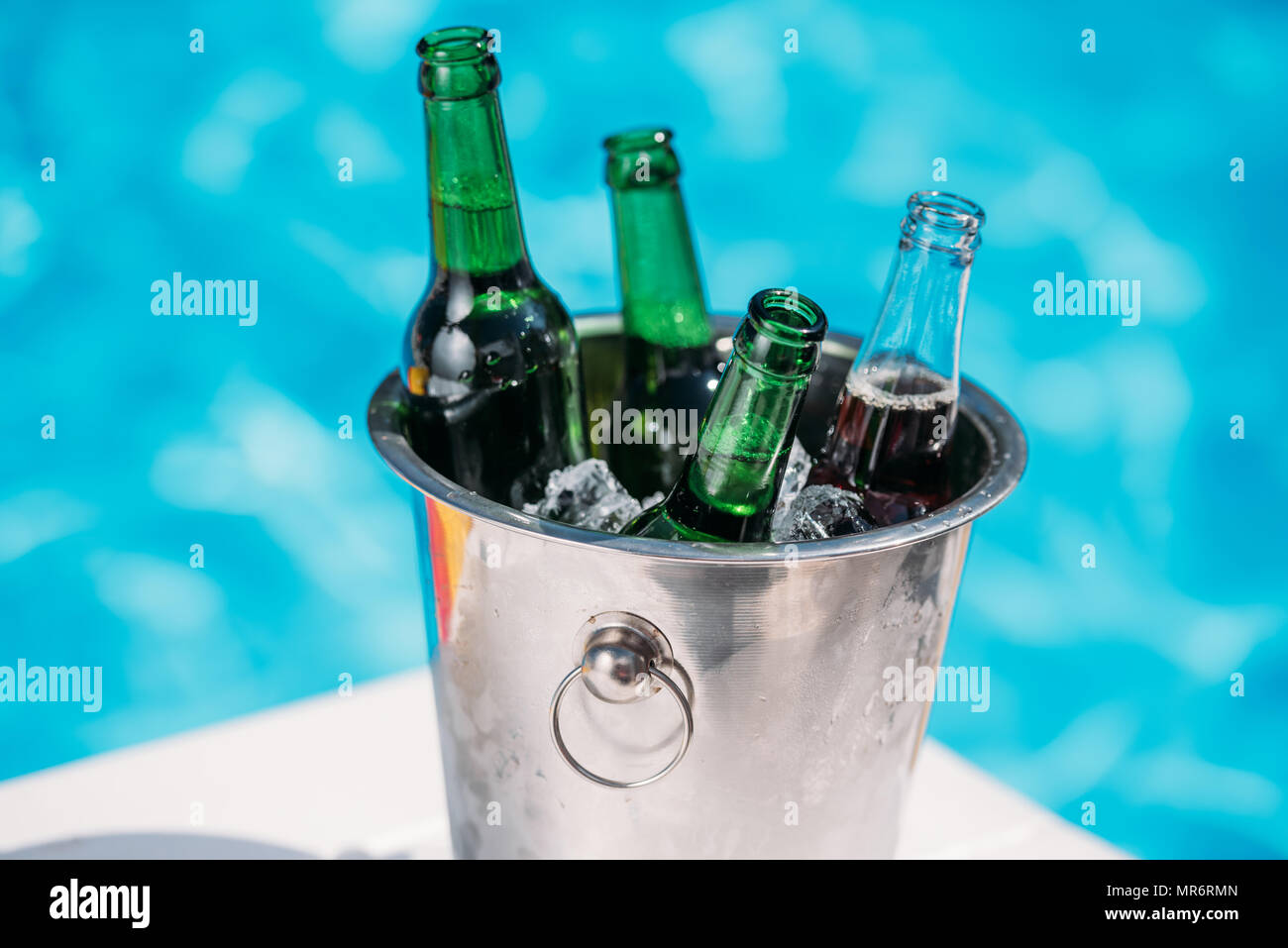 Close-up view of Ice bucket with beer standing next to swimming pool ...