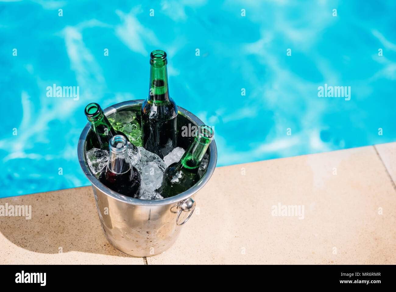 Close-up view of Ice bucket with beer standing next to swimming pool ...