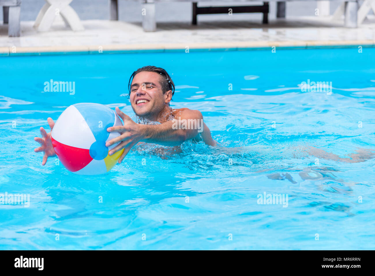 Young happy caucasian man playing with ball in swimming pool Stock ...