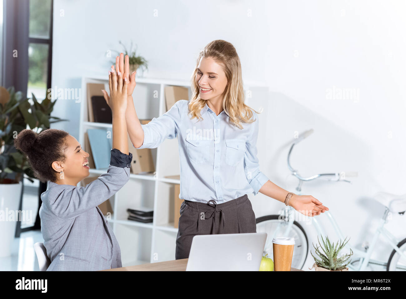 happy multiethnic businesswomen giving high five to each other at ...