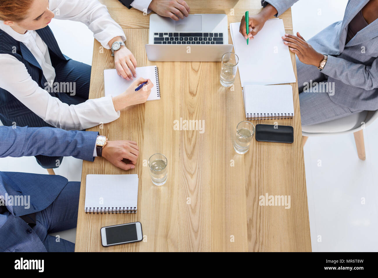 Business team writing in notepads during meeting in office Stock Photo ...