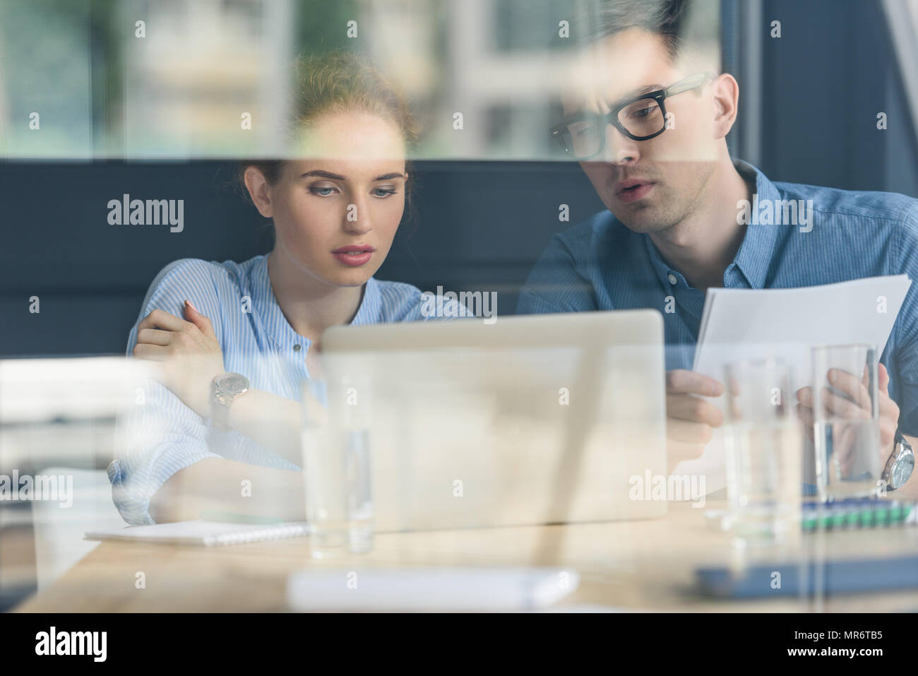 Behind the glass view of thoughtful businessman and businesswoman ...
