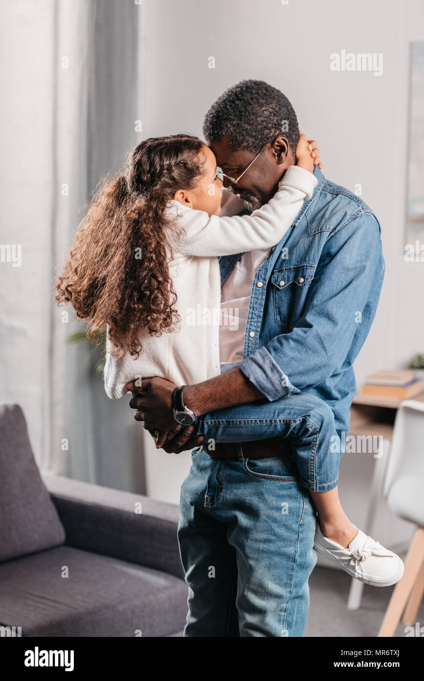 Loving african american girl embrace father that holding her on hands ...