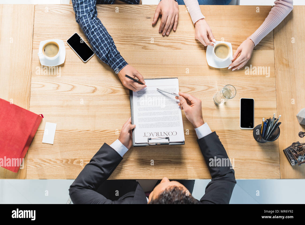 overhead view of man signing contract at table during meeting with ...