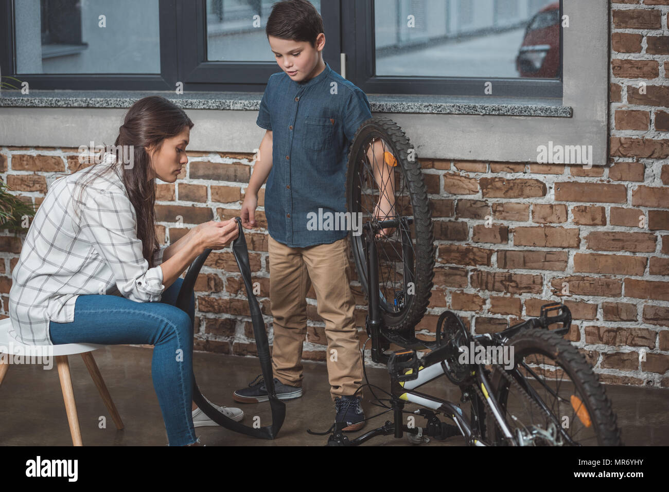 Young woman helping her little son to fix his bicycle wheel Stock Photo ... Young woman helping her little son to fix his bicycle wheel Stock Photo ...
