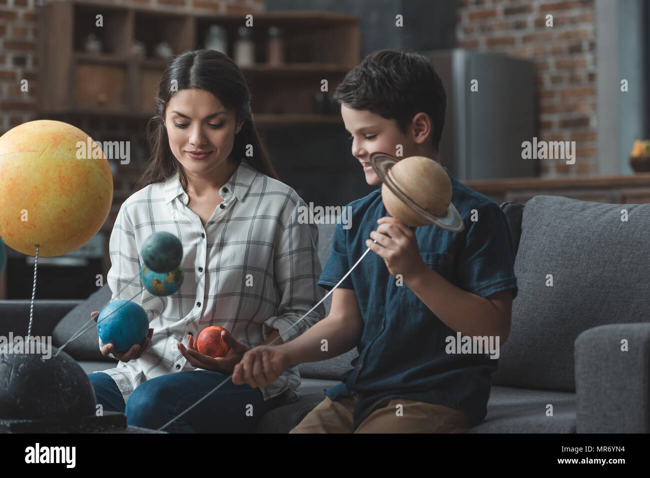 Little boy and his mother constructing a solar system model in living ...