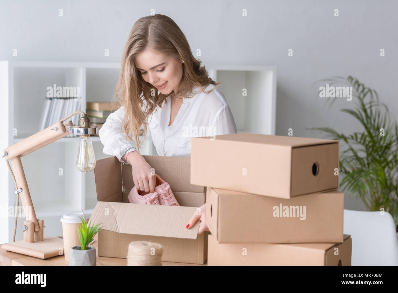 portrait of beautiful entrepreneur packing products for customers in ...