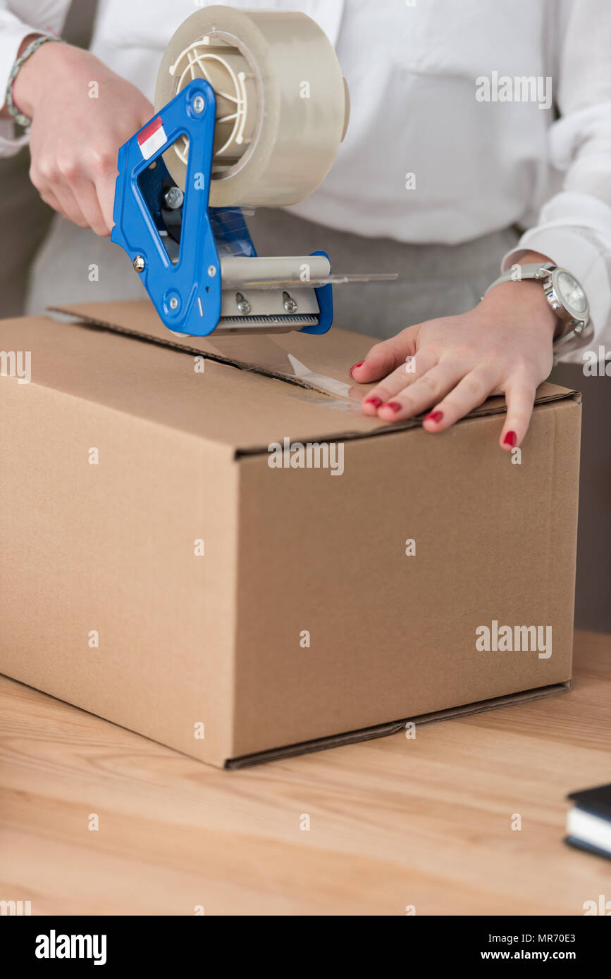 partial view of entrepreneur packing customers parcel with adhesive ...