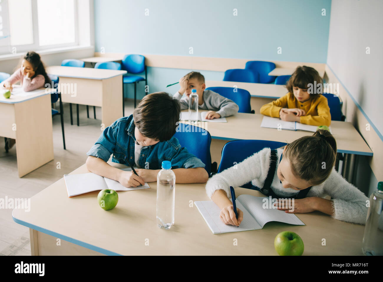 schoolchildren writing in notebooks on lesson at classroom Stock Photo ...
