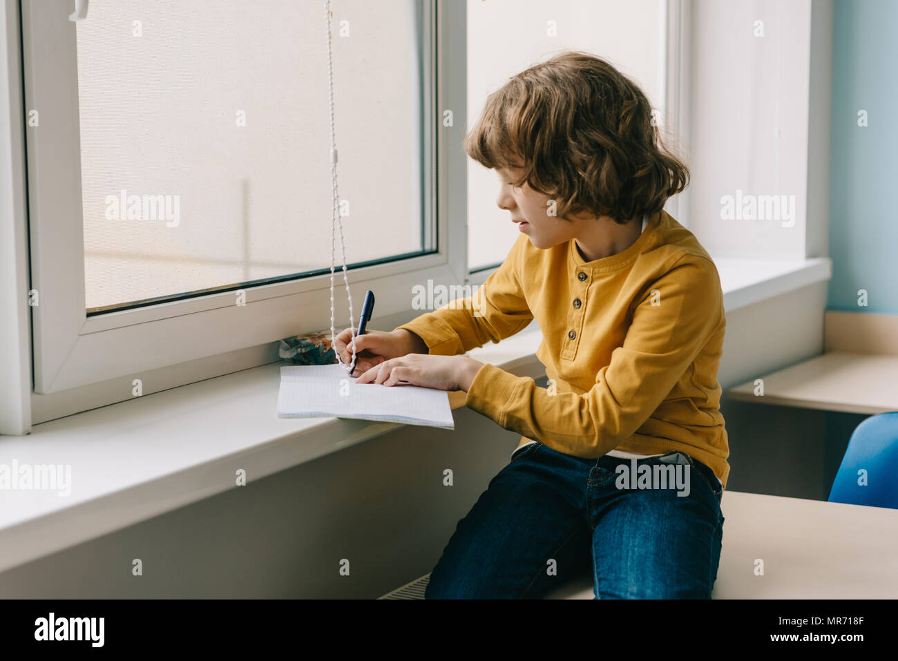 little kid writing homework on windowsill Stock Photo - Alamy