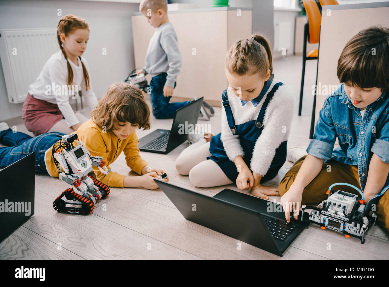 kids programming diy robots with laptops while sitting on floor, stem ...