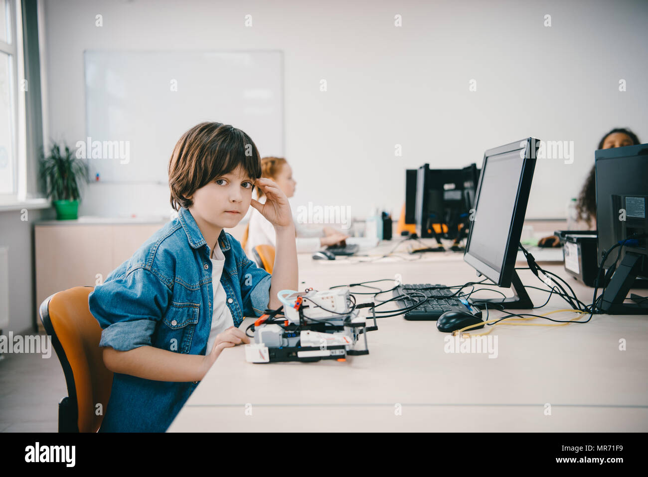 teen kid looking at camera while programming diy robot at machinery ...