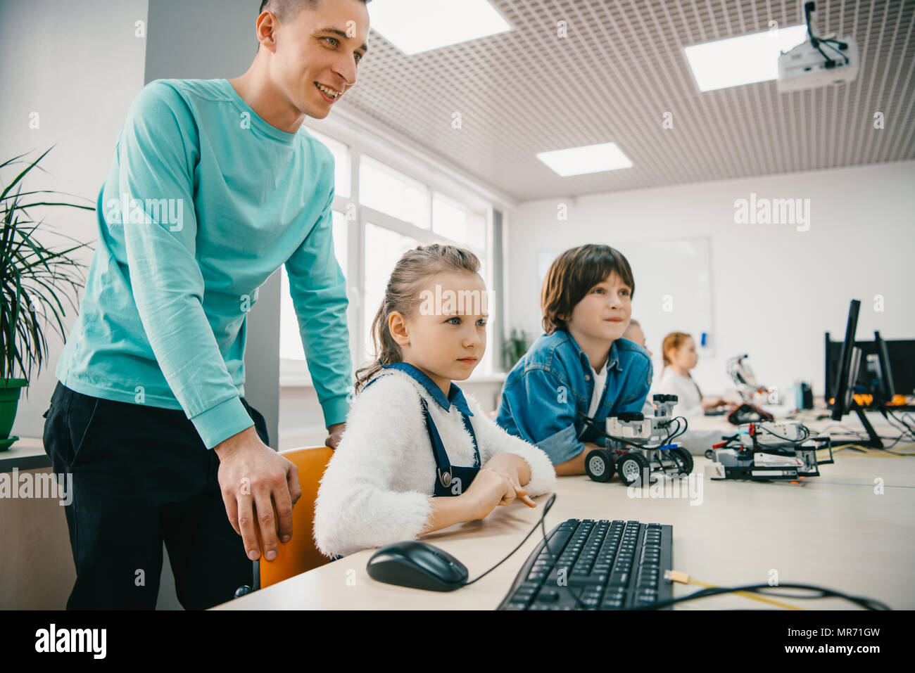 young teacher helping his teen students with diy robot on stem ...