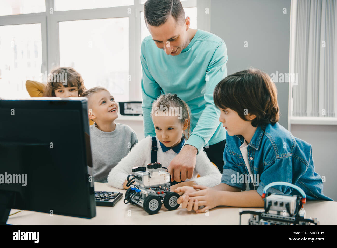 teacher working with teen students on diy robot on stem education class ...