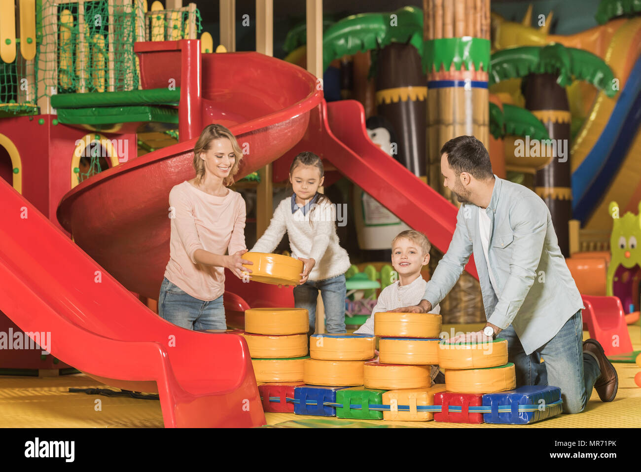 happy parents with adorable little kids playing together in game center ...