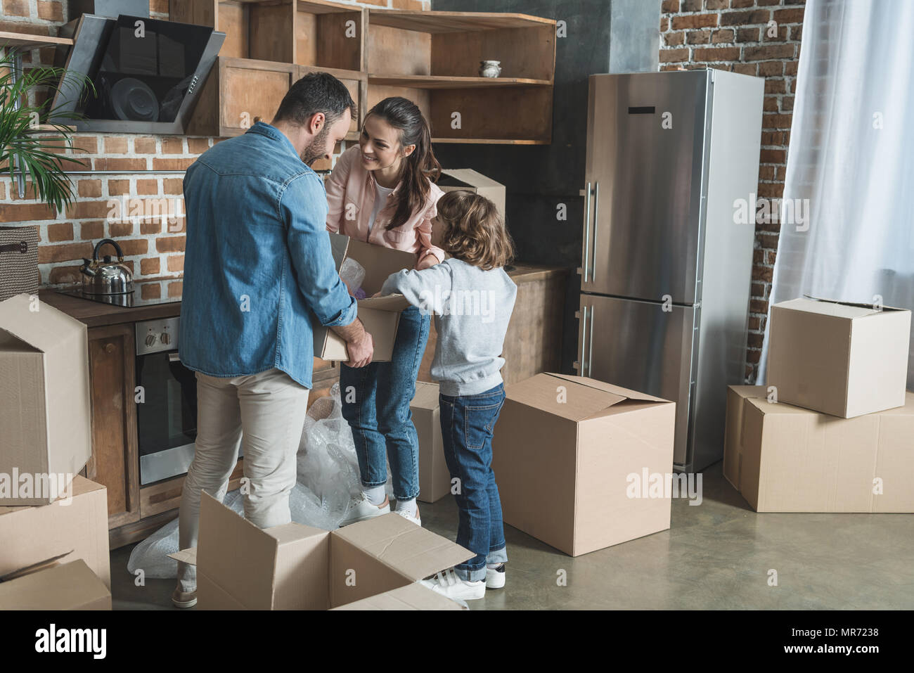 happy family packing cardboard boxes while moving home Stock Photo - Alamy