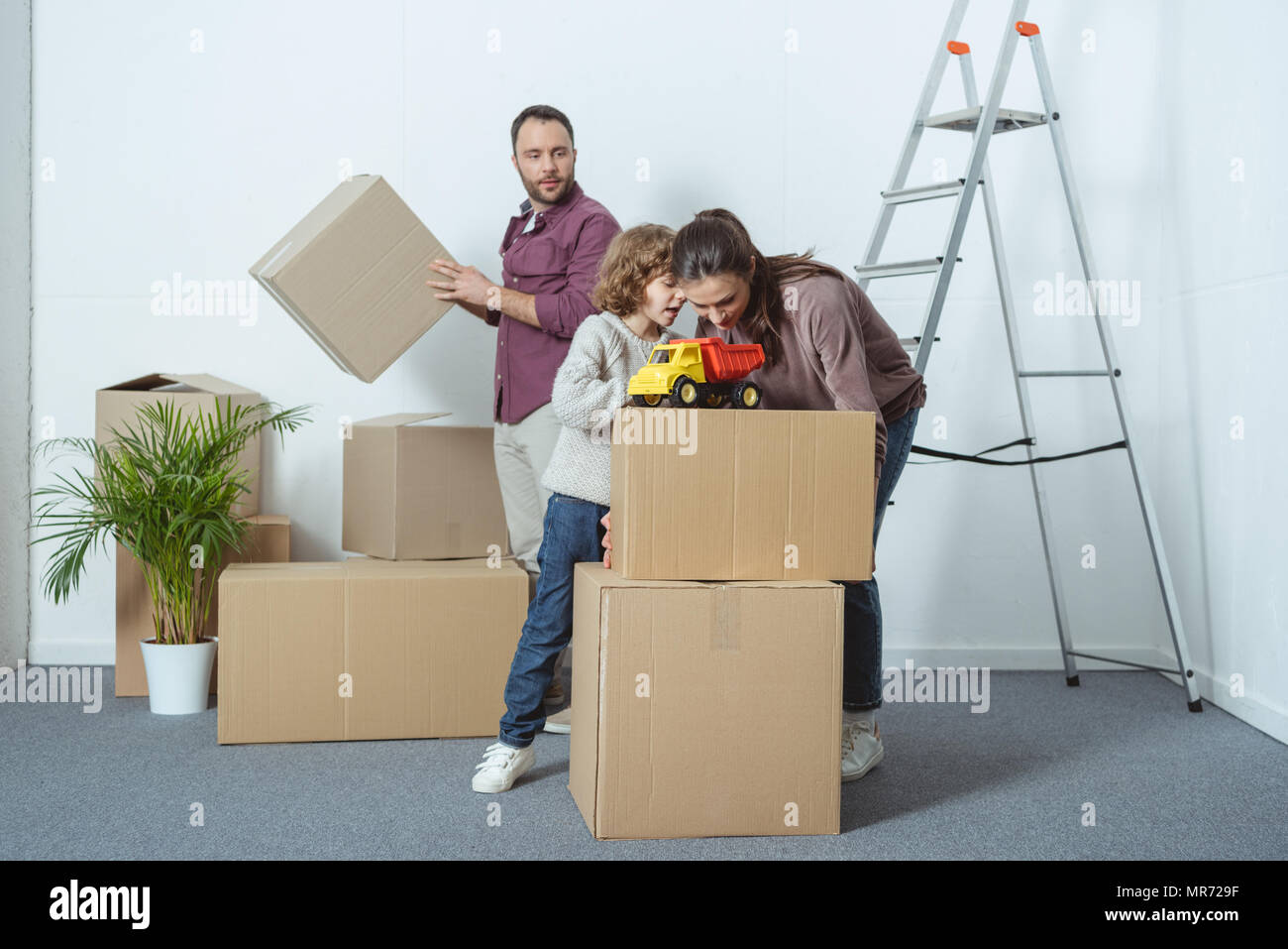 family with one child packing cardboard boxes while moving home Stock ...