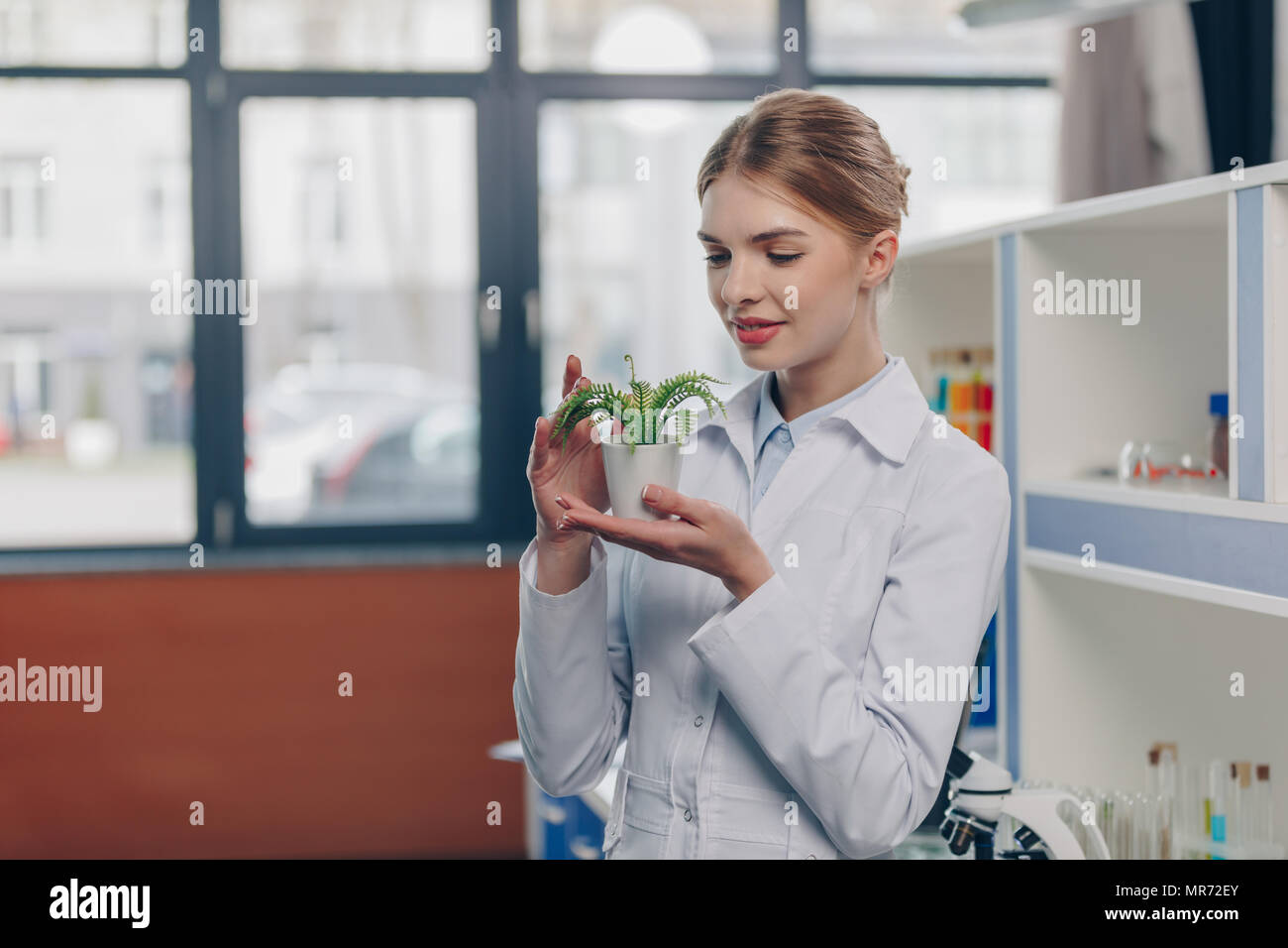 female biologist in white coats holding fern plant in laboratory Stock ...