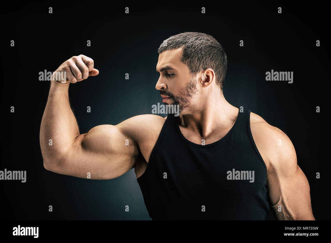 portrait of strong man showing muscles isolated on black Stock Photo ...