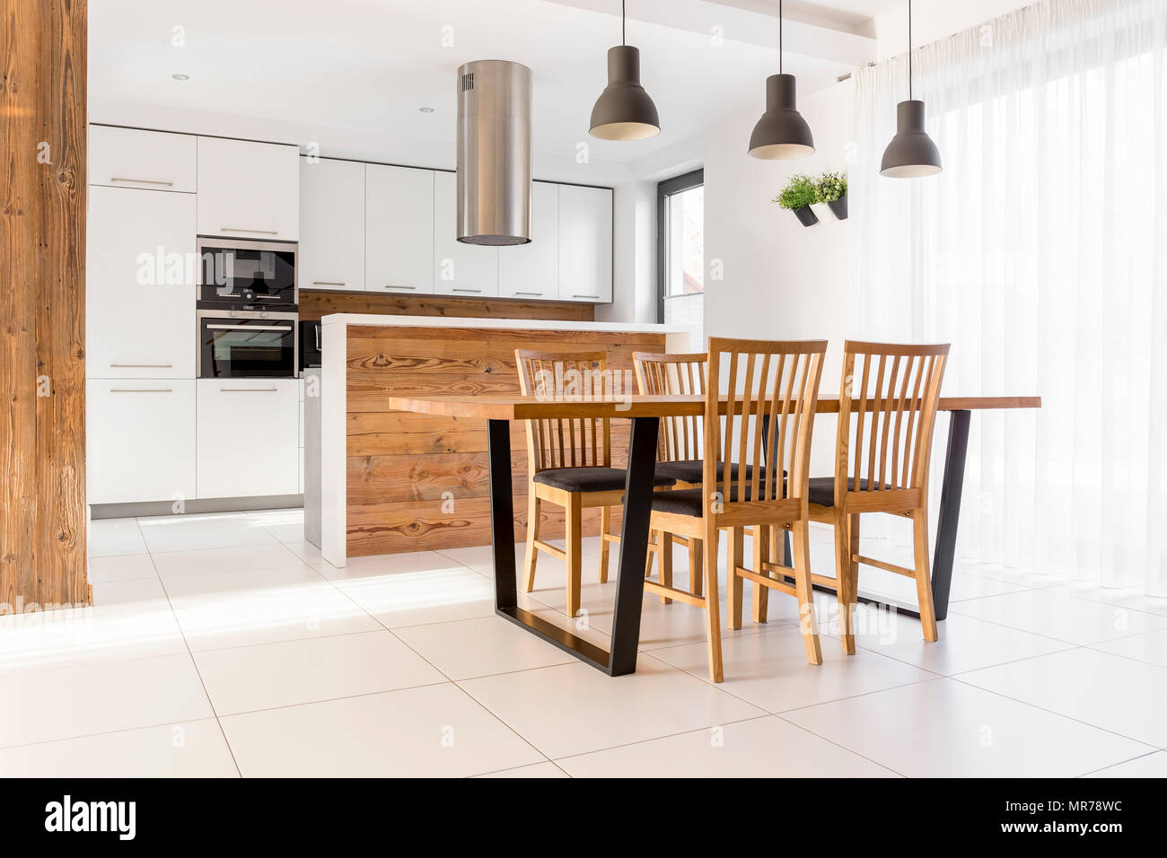 New white kitchen with wood table, chairs and island Stock Photo - Alamy