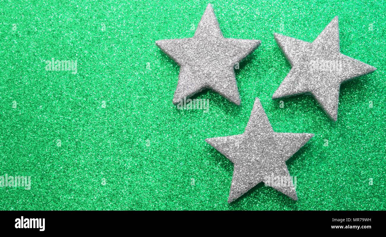 three large silver stars on green glittery background Stock Photo - Alamy