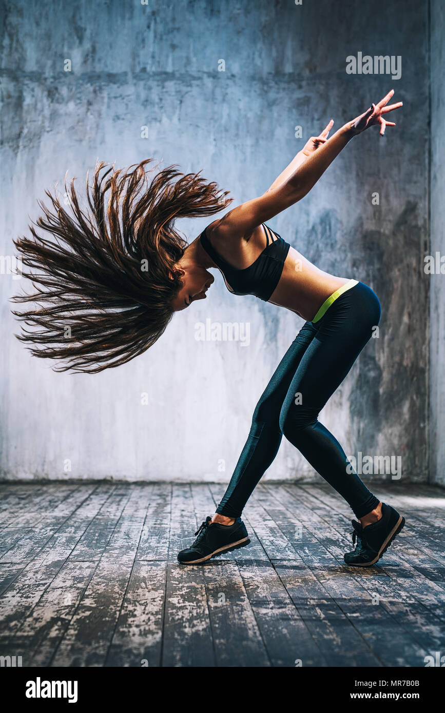 Young sports slim woman shaking hair on stone wall background Stock ...