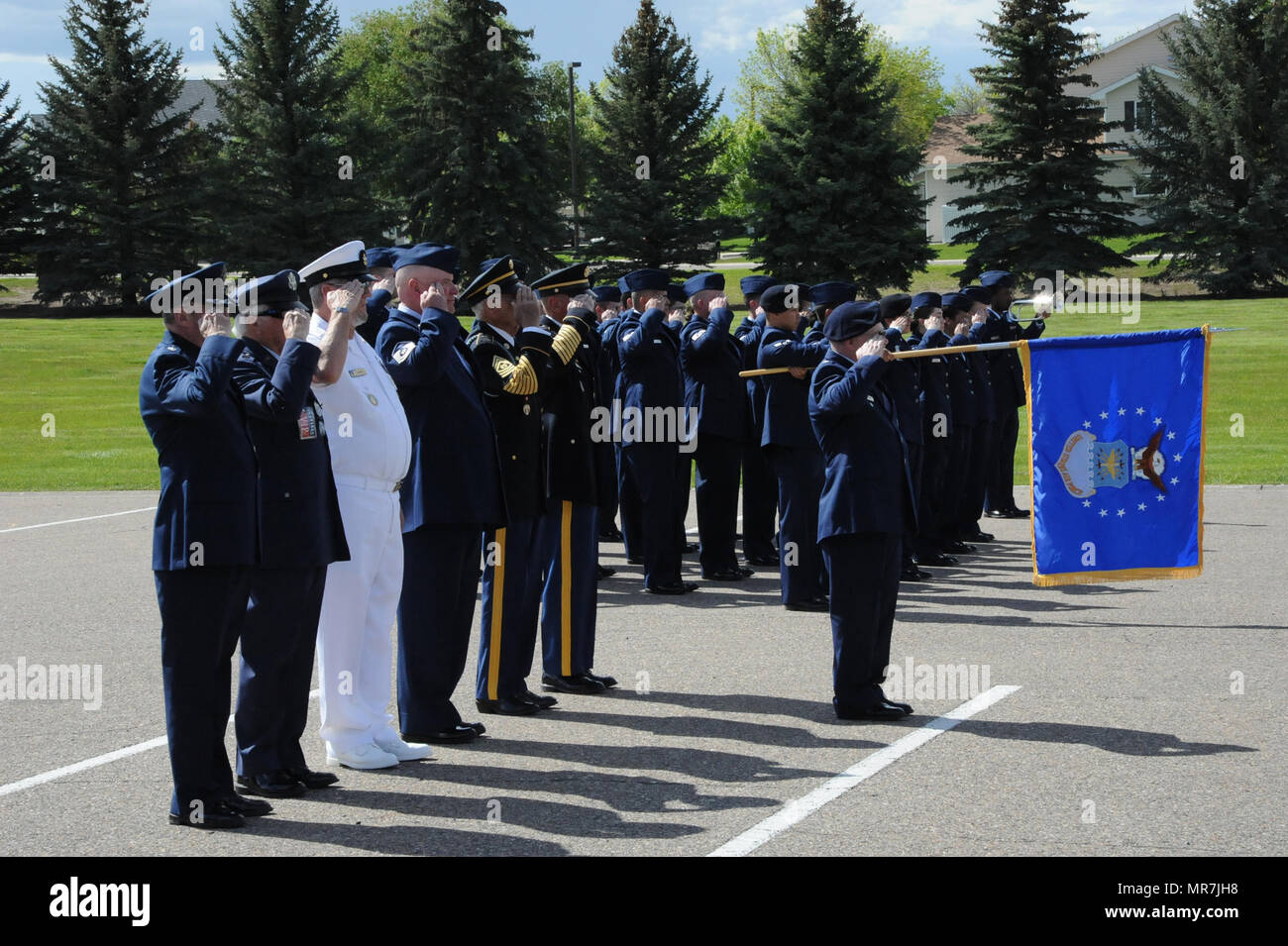 Active-duty Airmen and retired military members salute while taps is ...