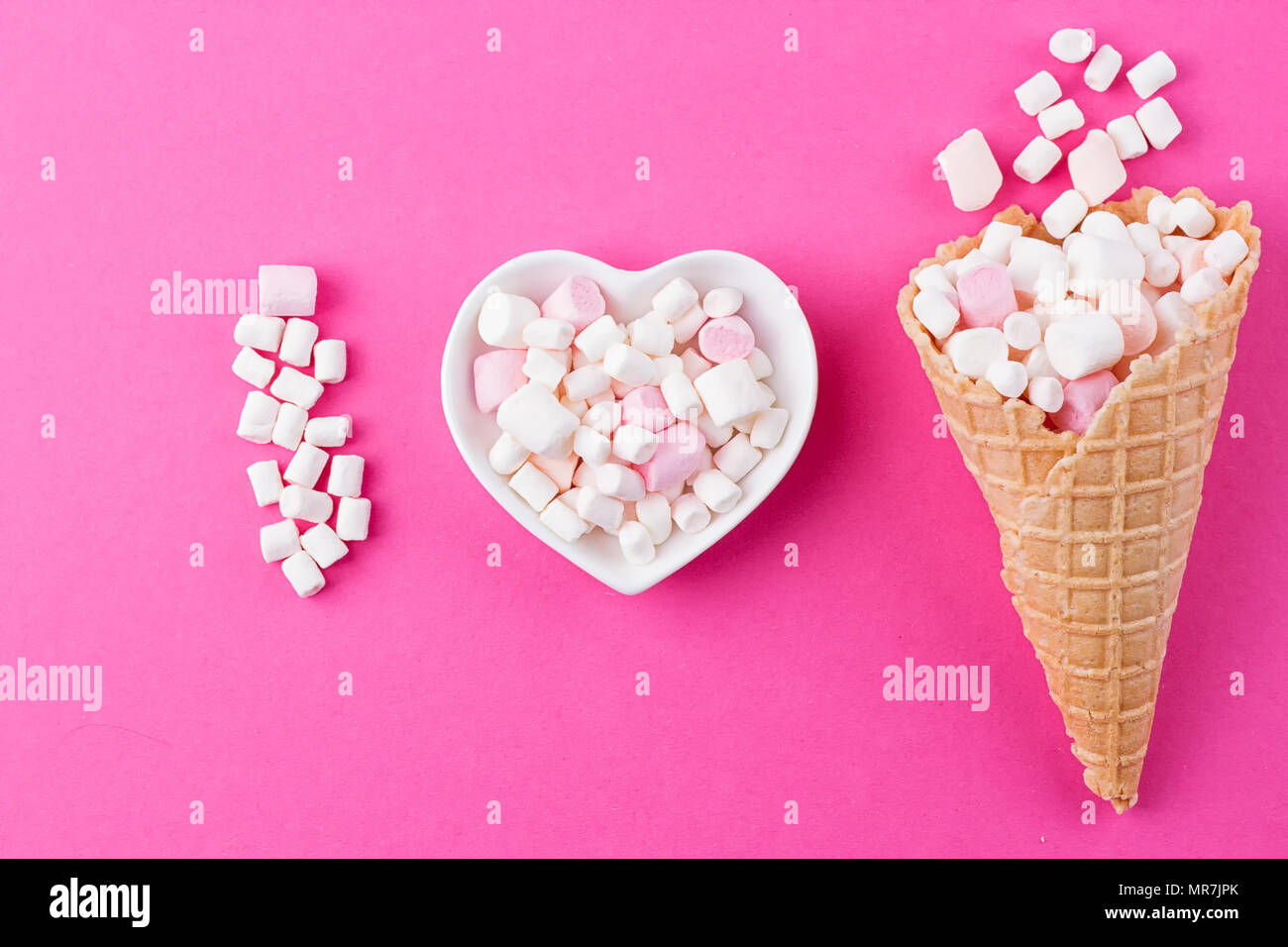 Love concept. Plate in the shape of heart with a marshmallow on a pink ...