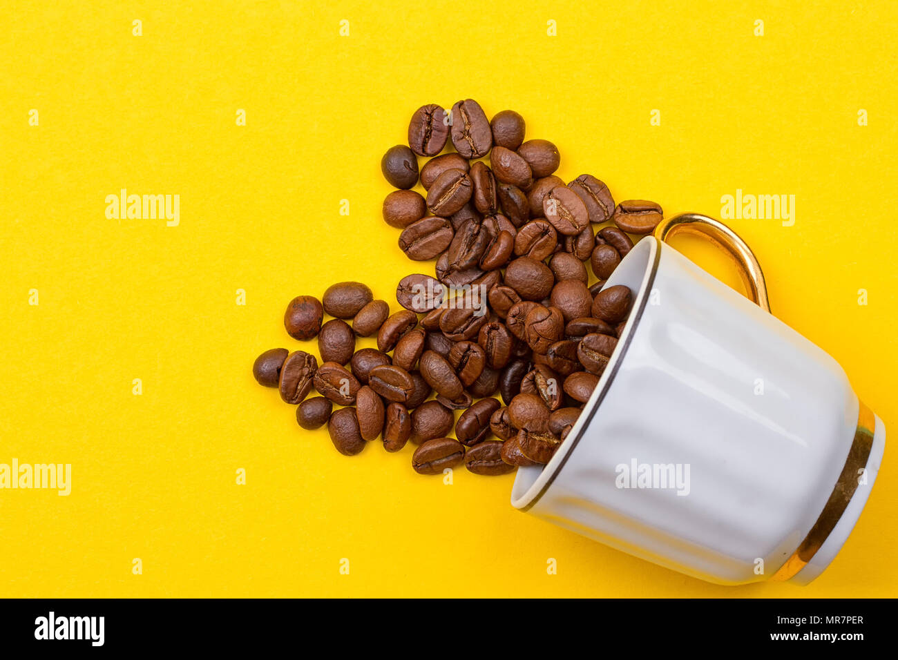 coffee beans spilled out of a cup on the yellowbackground Stock Photo ...