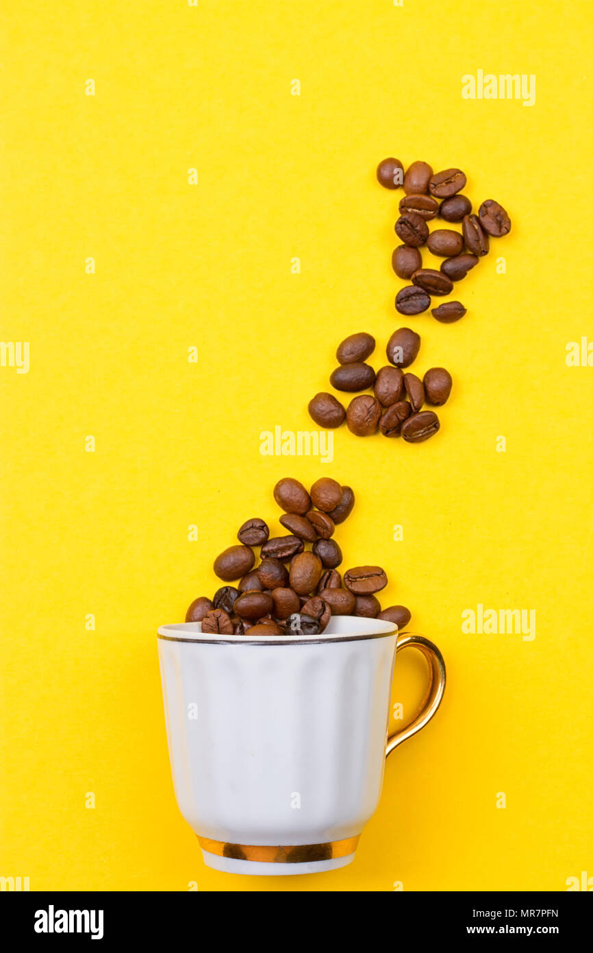 coffee beans spilled out of a cup on the yellowbackground Stock Photo ...