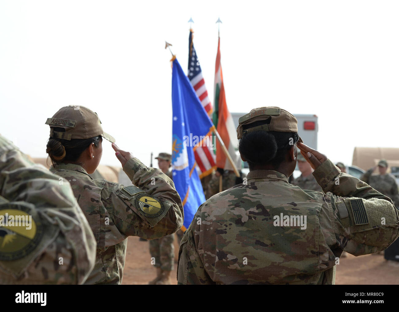 Airmen render a salute to the displayed flags of the United States and ...
