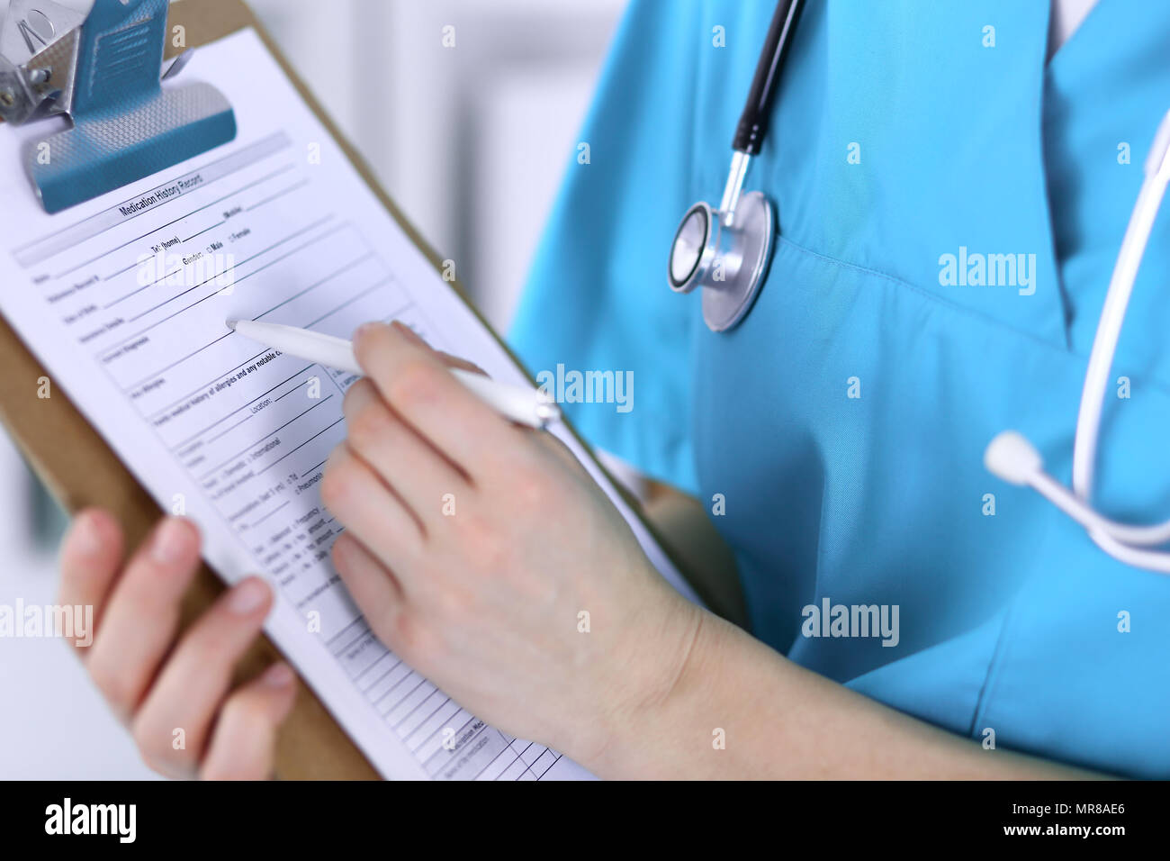 Female doctor filling up medical form on clipboard closeup. Physician ...
