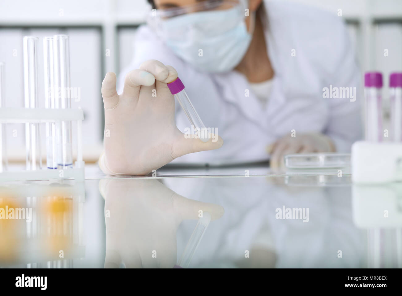 Close-up of professional female scientist in protective eyeglasses ...