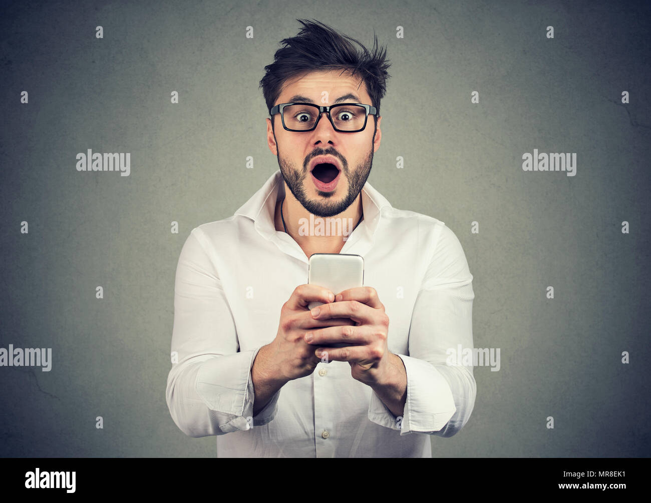 Young handsome bearded man in shirt holding new smartphone and looking ...