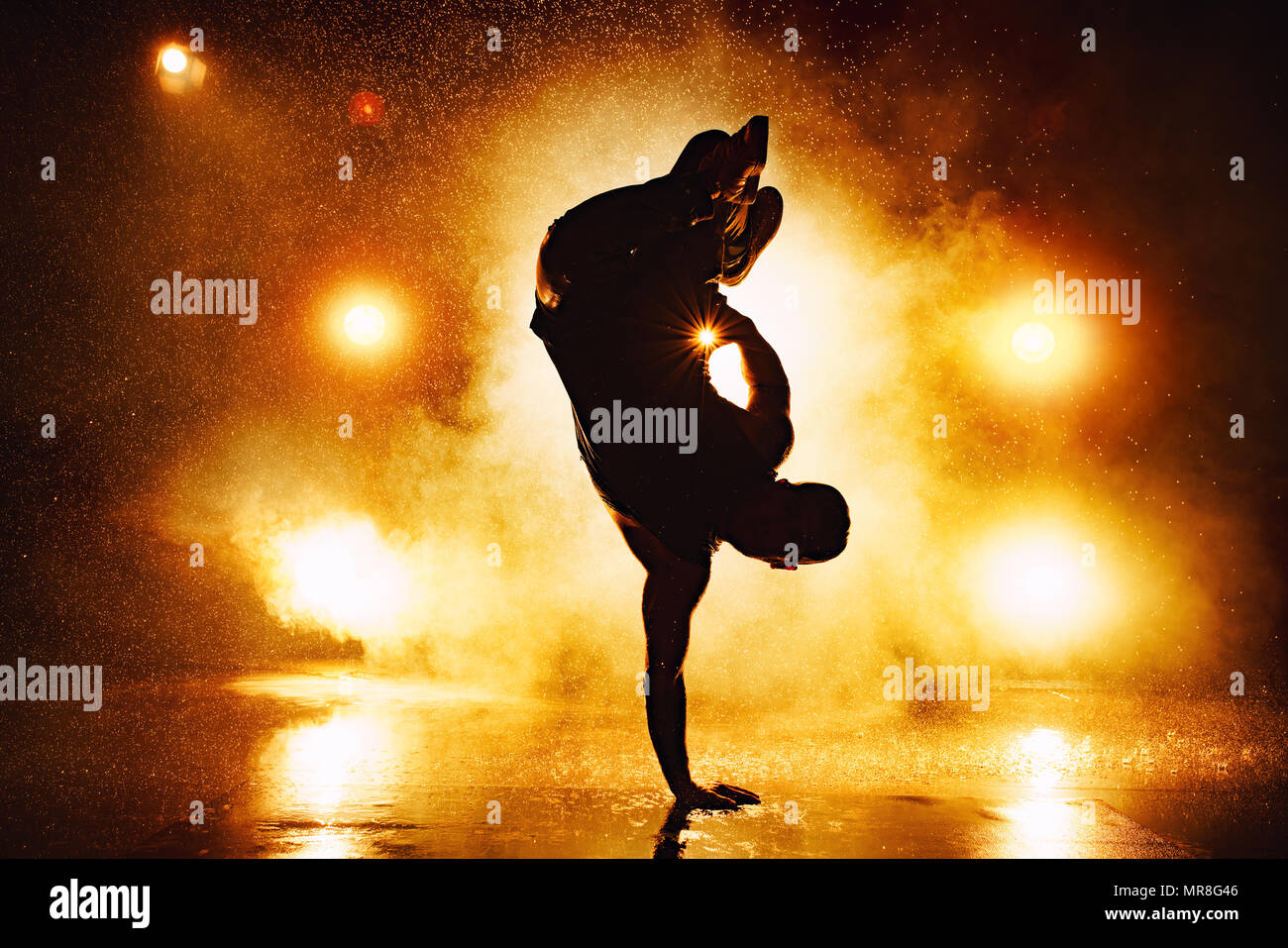 Young man break dancer dramatic silhouette standing on hand in club ...