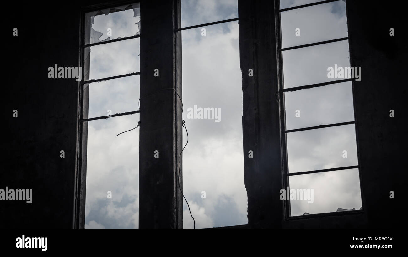 Broken window in an abandoned building - View from inside - sky with ...