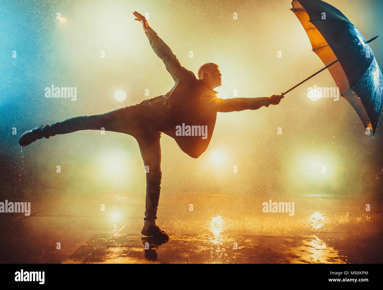 Young strange man dancing with umbrella under the rain. Vibrant lights ...
