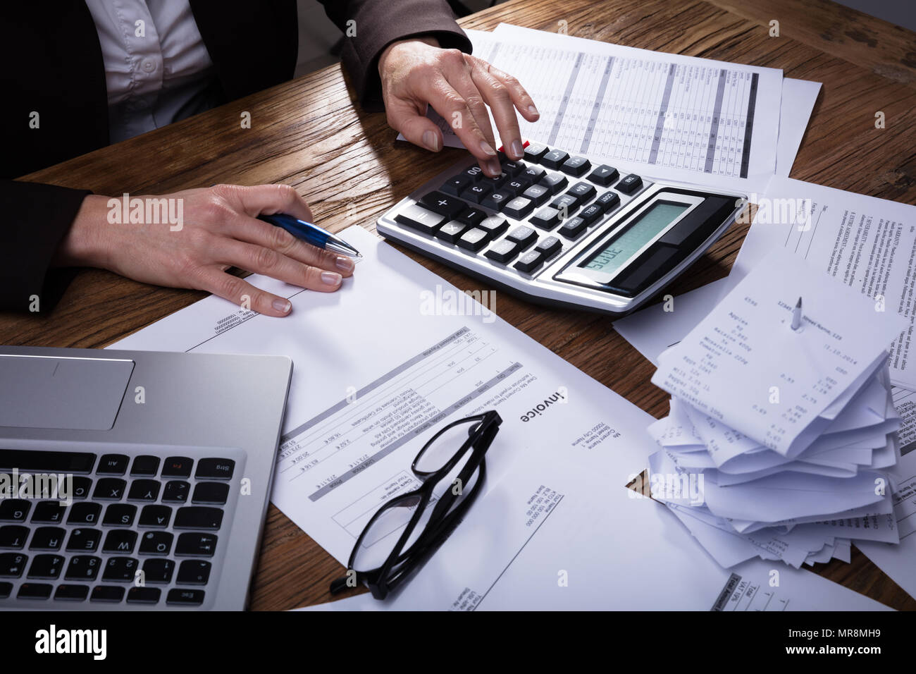 Businessperson Calculating Invoice With Calculator In Office Stock ...