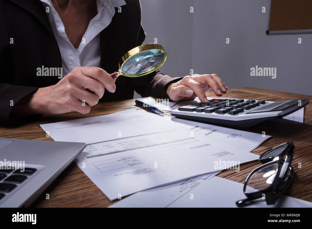 Businessperson's Hand Analyzing Invoice Through Magnifying Glass In ...