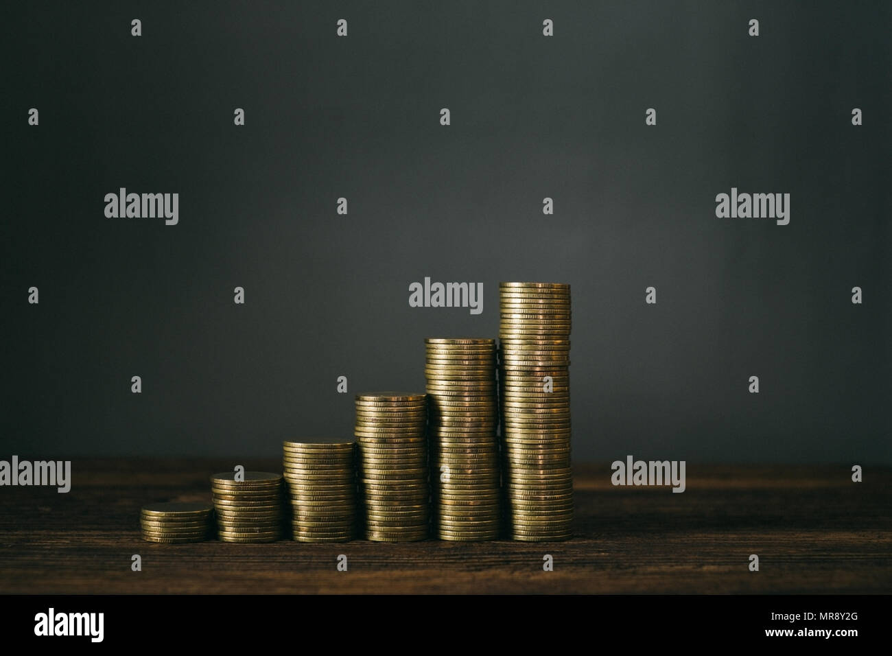 Increasing columns of coins, step of coins stacks on wooden table with ...