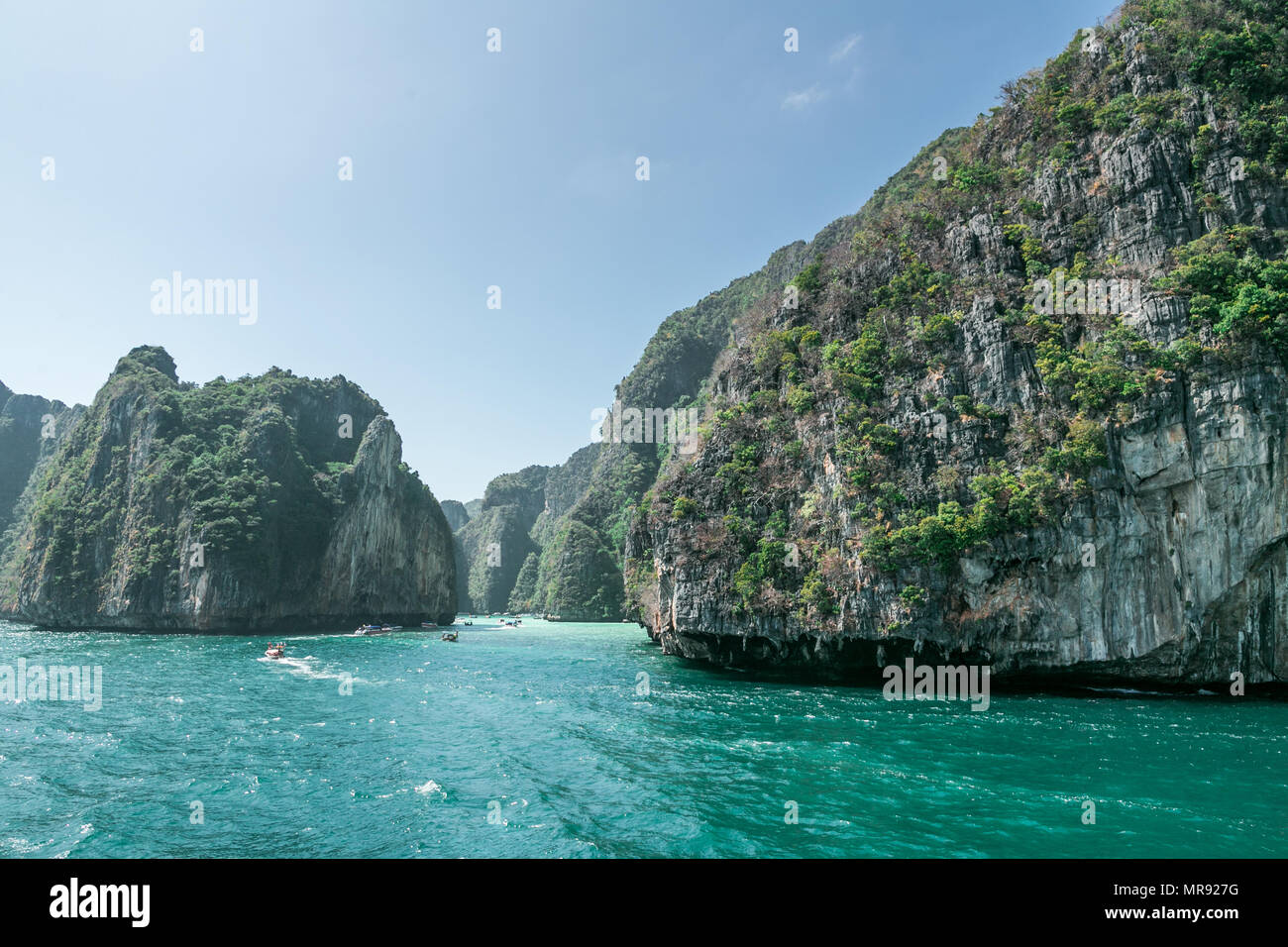 scenic view of rocky formations covered with green plants, blue sky and ...