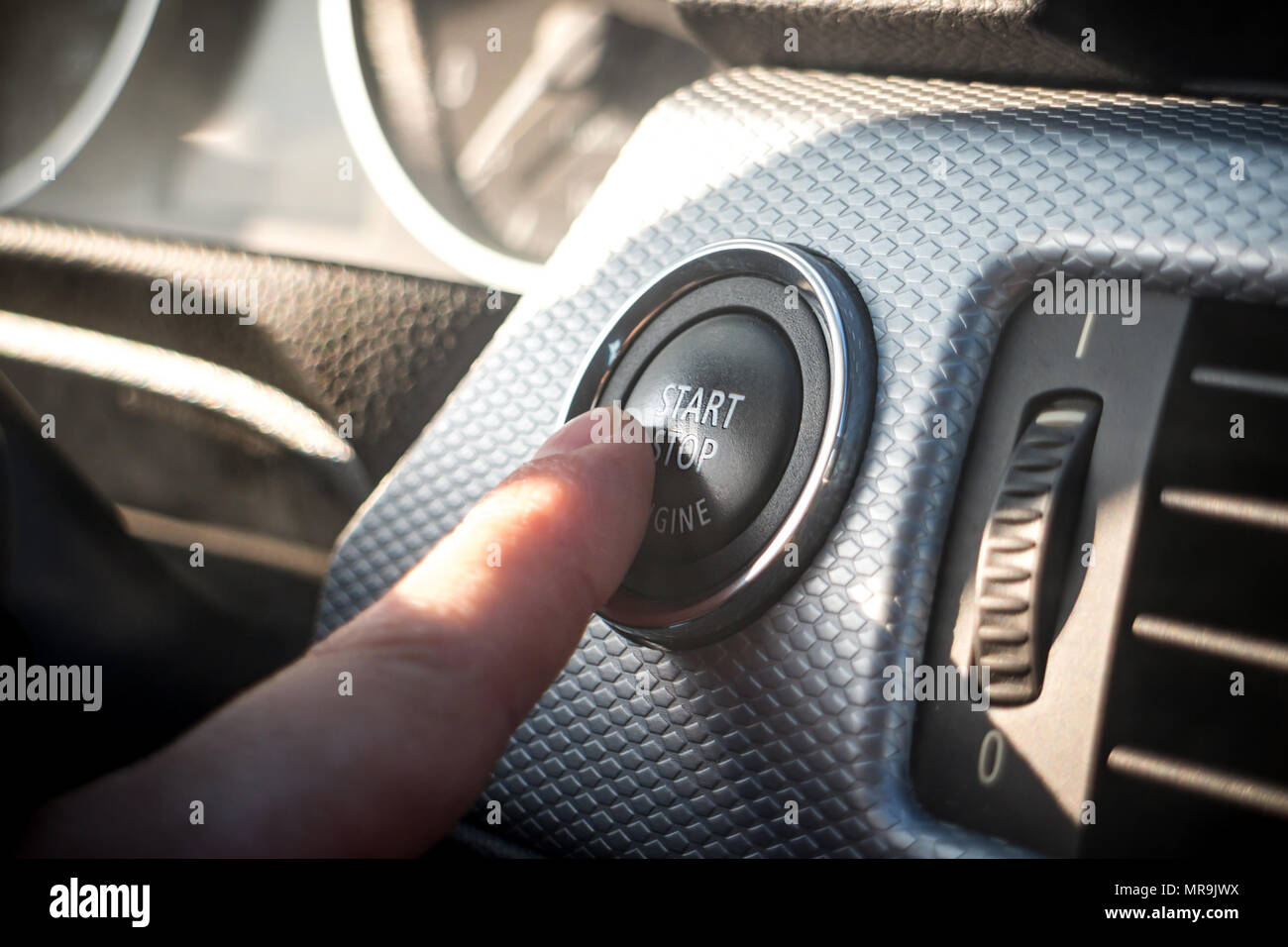 Girl pressing the Start stop engine button on modern car dashboard ...