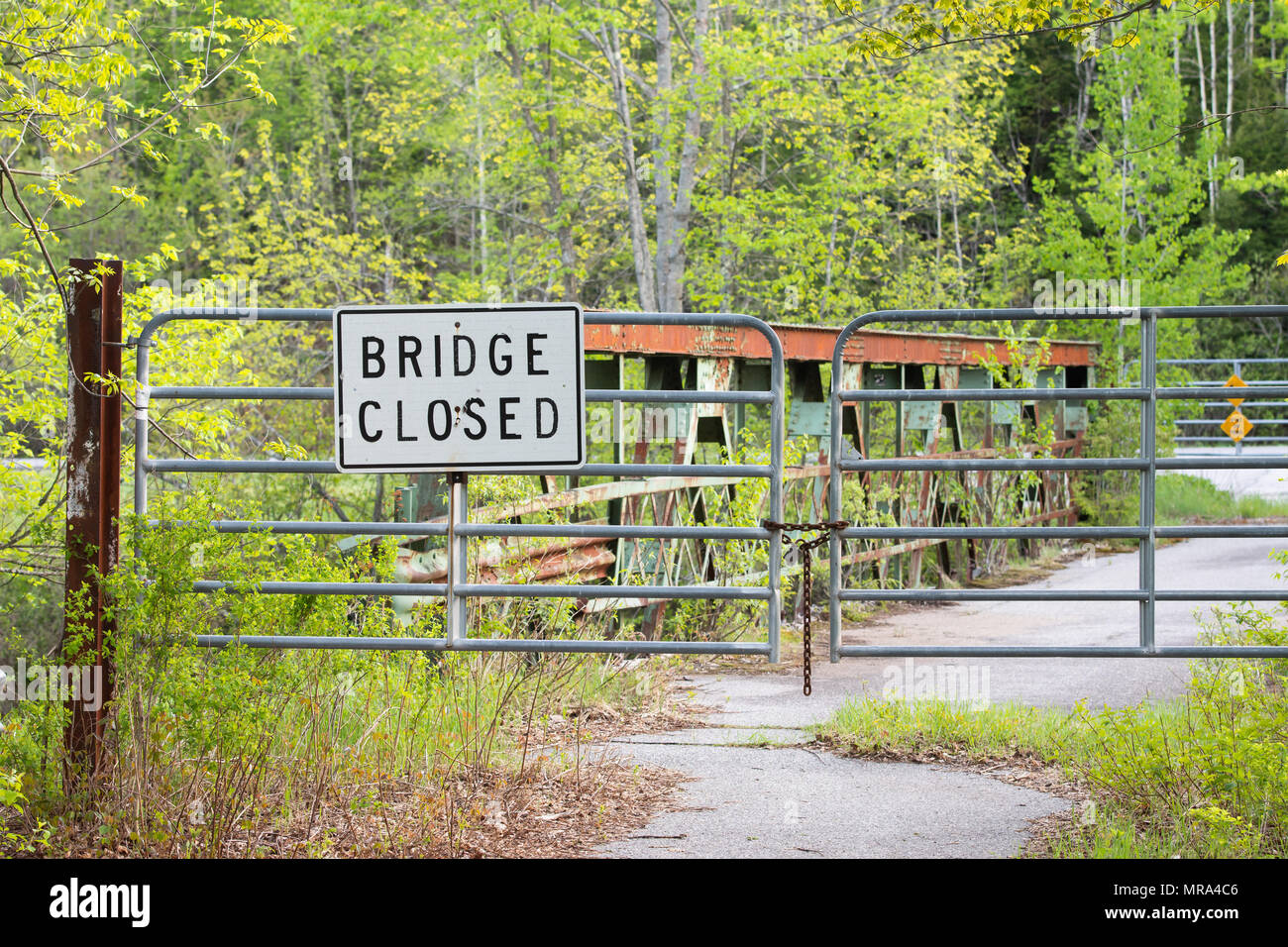 A gate with a bridge closed sign on an unused neglected bridge over the ...