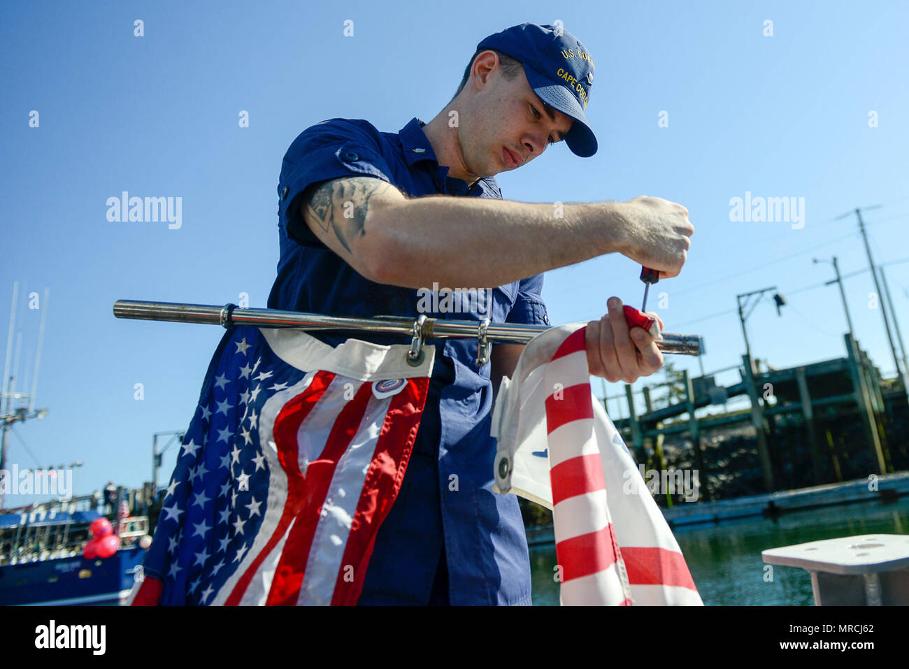 U.S. Coast Guard Petty Officer 3rd Class Ian Burgess unscrews the Coast ...